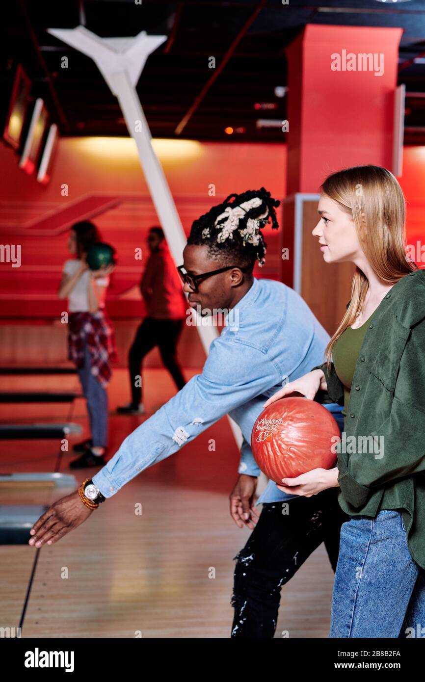 African guy with stretched arm explaining his girlfriend how to throw ...