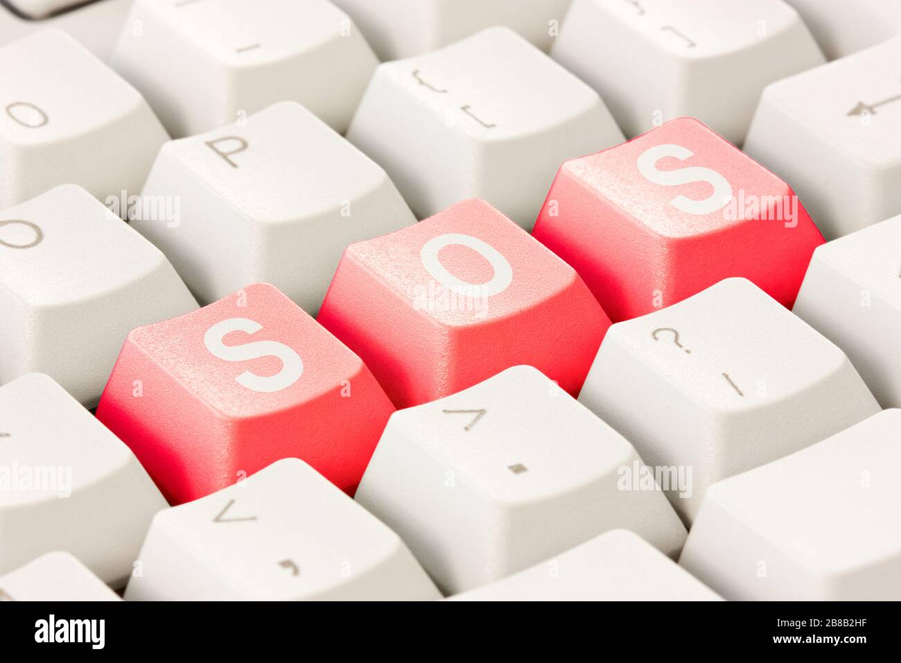 White computer keyboard with red keys arranged in the word SOS ...