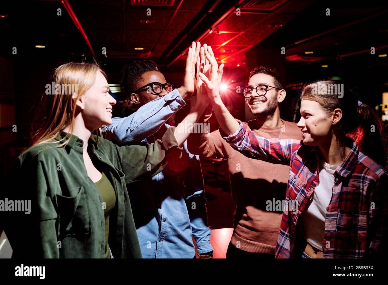 Group of young cheerful intercultural friends giving each other high ...