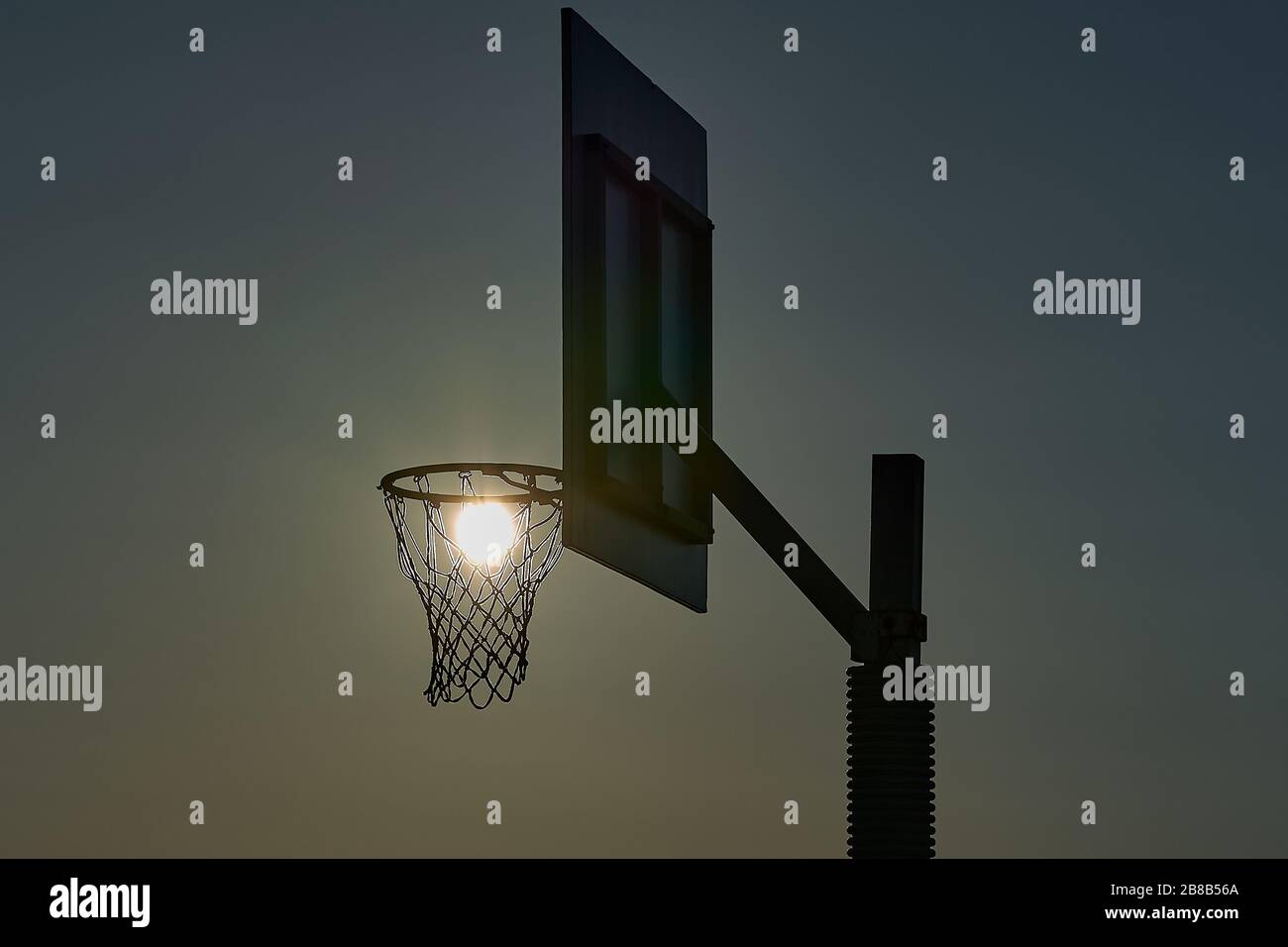 Silhouette of basketball ring in the court with a glowing sun and a ...