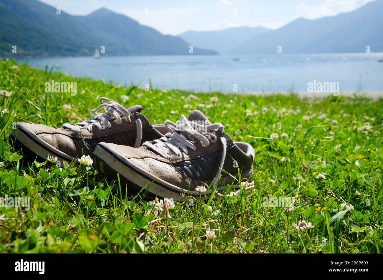 Closeup shot of shoes on the green grass on the waterfront with ...