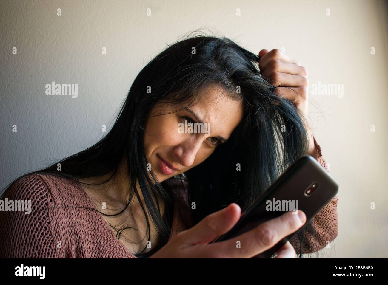 Beautiful black girl holding smartphone and adjusting hair Stock Photo ...