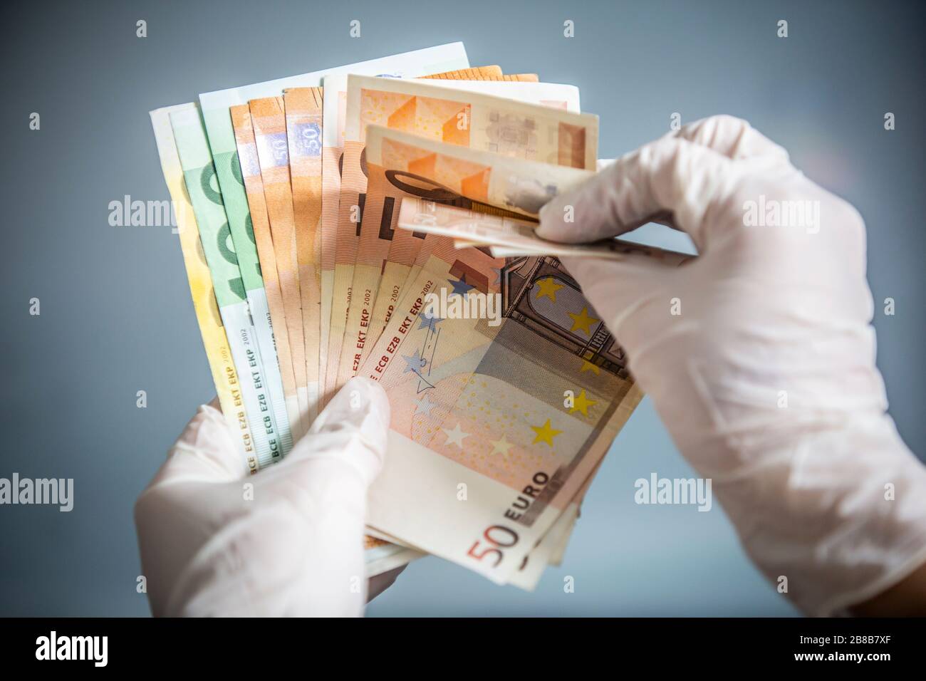 Man holding Euro currency bills with hands wearing surgical gloves to ...