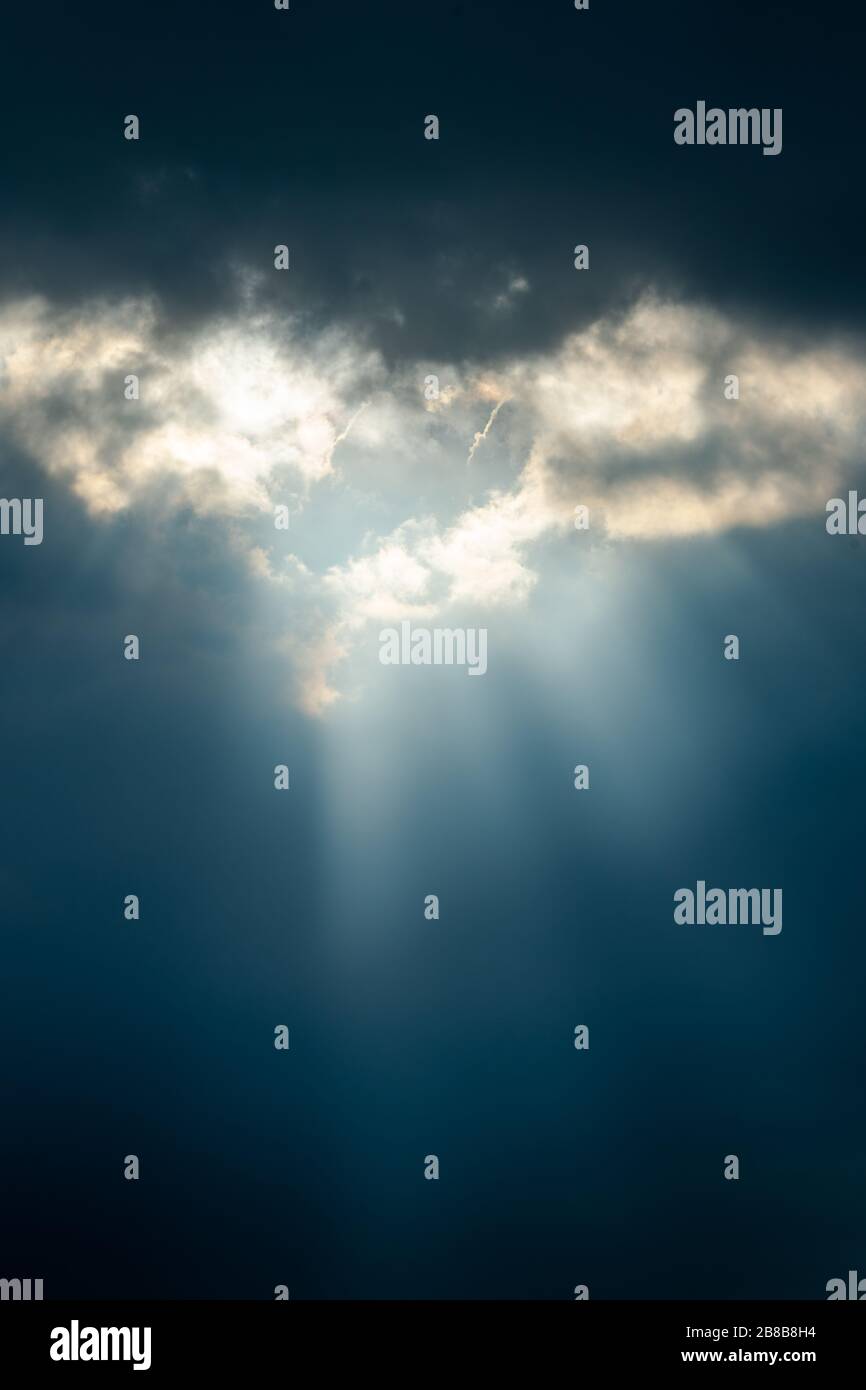 Dramatic sun rays breaking through the clouds on a very dark day ...