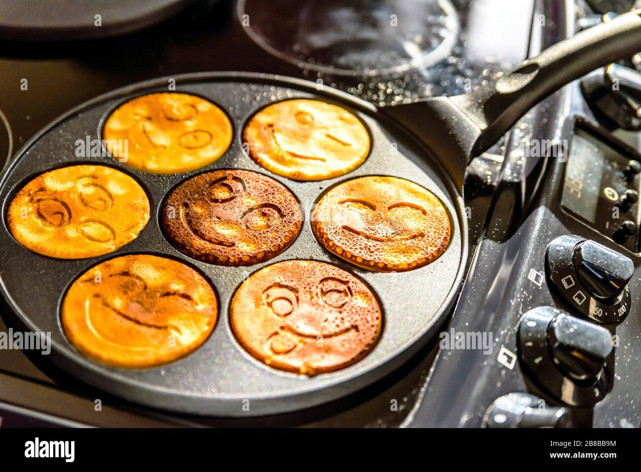 pancake frying pan with smile face pancake cooking on cooker in kitchen ...