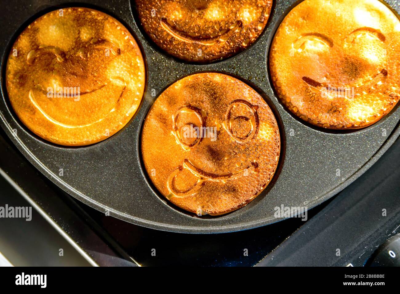 pancake frying pan with smile face pancake cooking on cooker in kitchen ...
