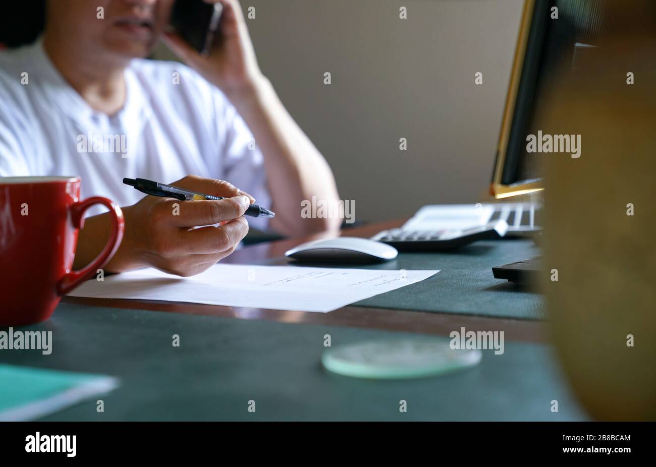 Man working from home, on his cell phone and facing computer screen ...