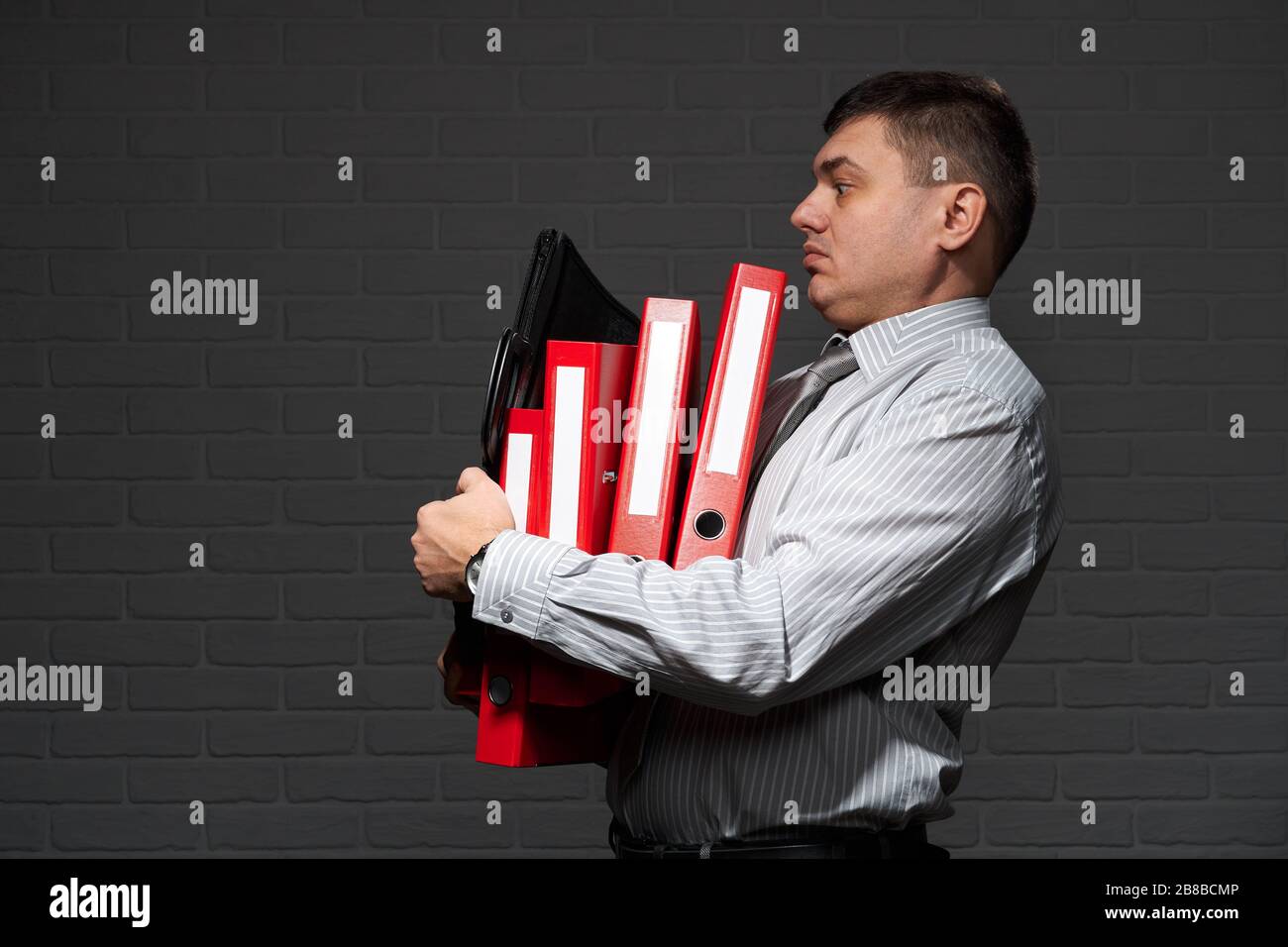 Very busy businessman closeup portrait, posing with red folders ...