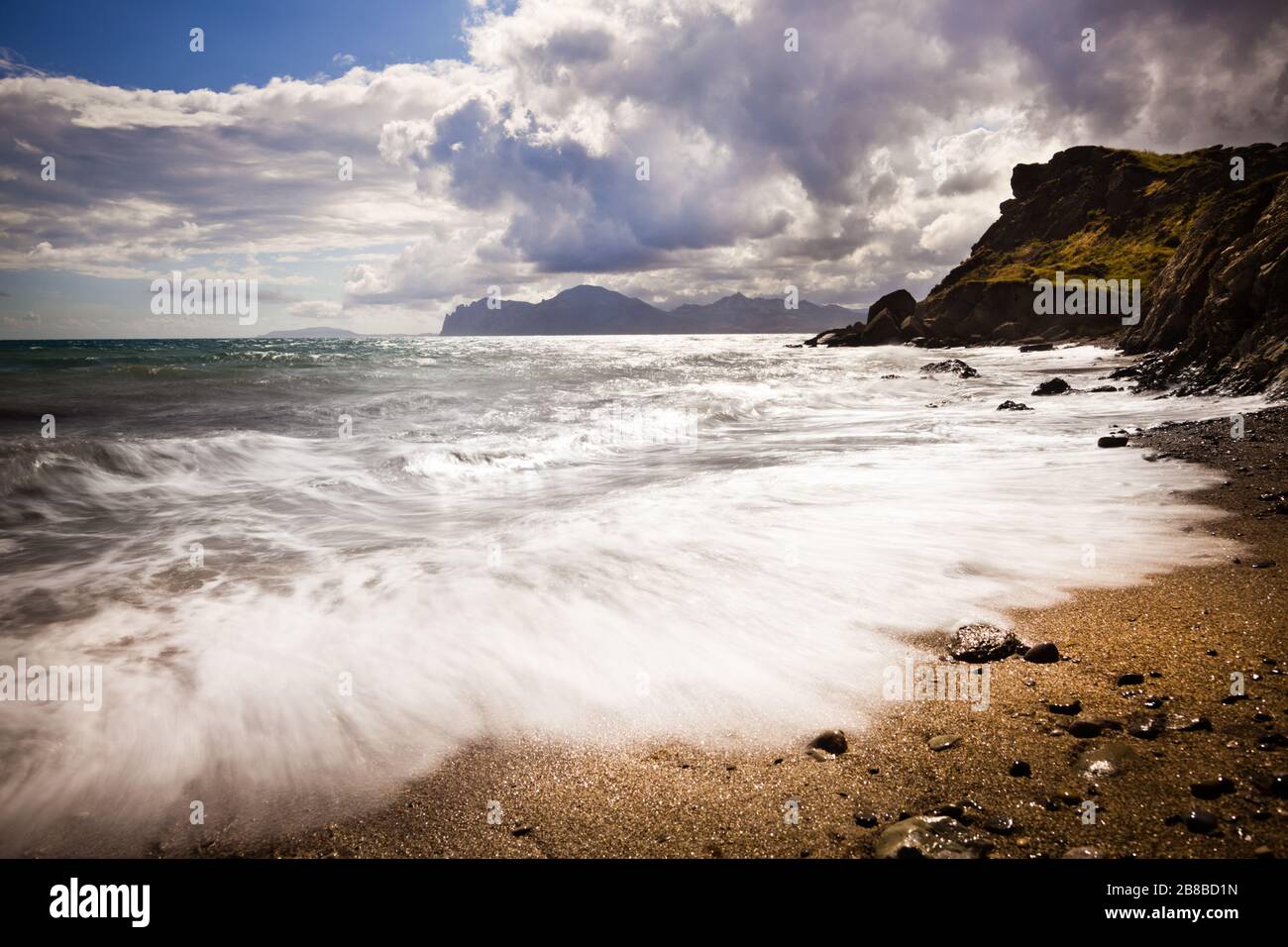 Sandy beach with mountains on background. Mountains are covered with ...
