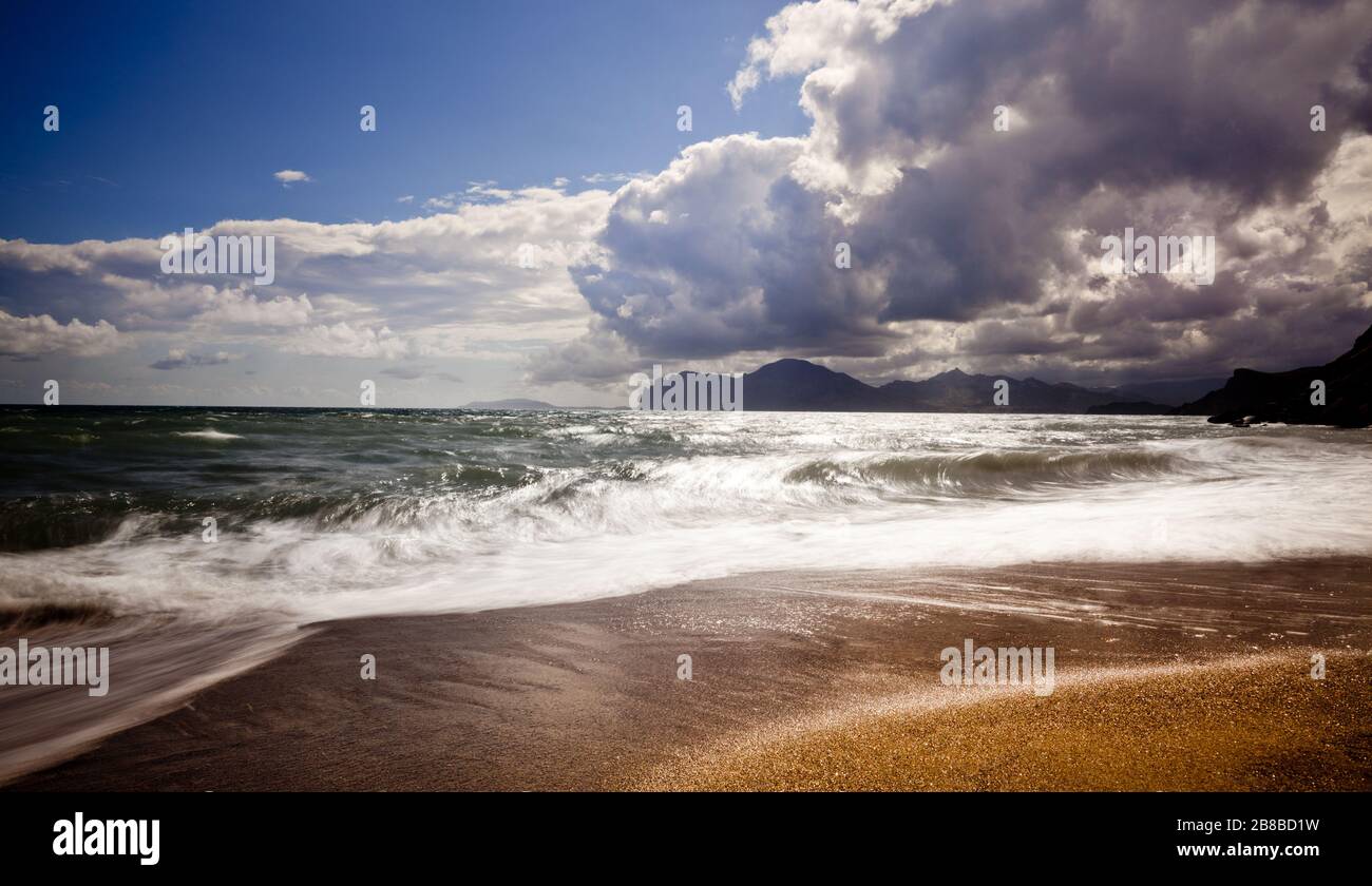 Sandy beach with mountains on background. Mountains are covered with ...