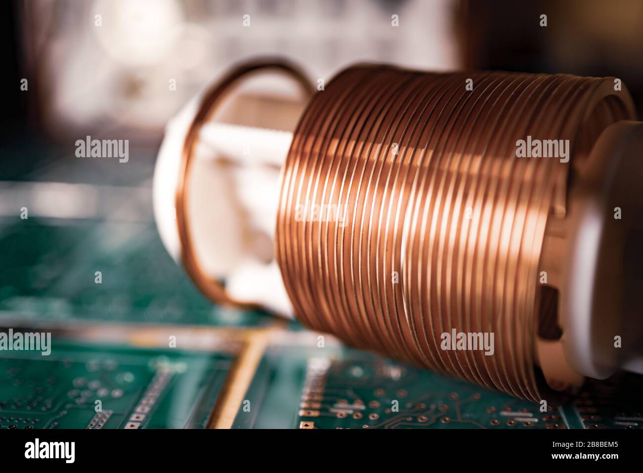 Close-up of a coil of copper wire standing on a large microcircuit ...