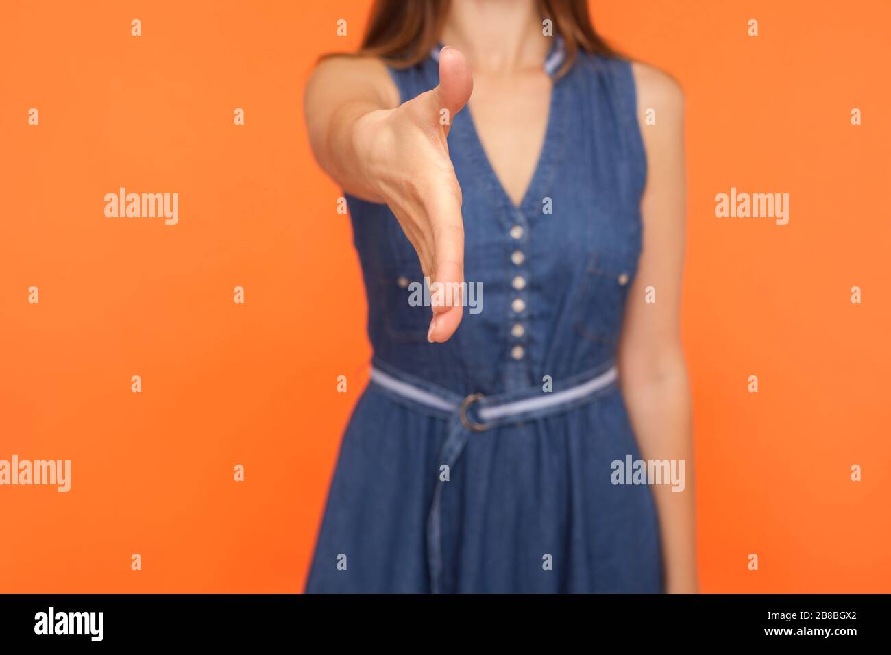 Closeup of woman in denim dress giving hand to handshake, stretching ...