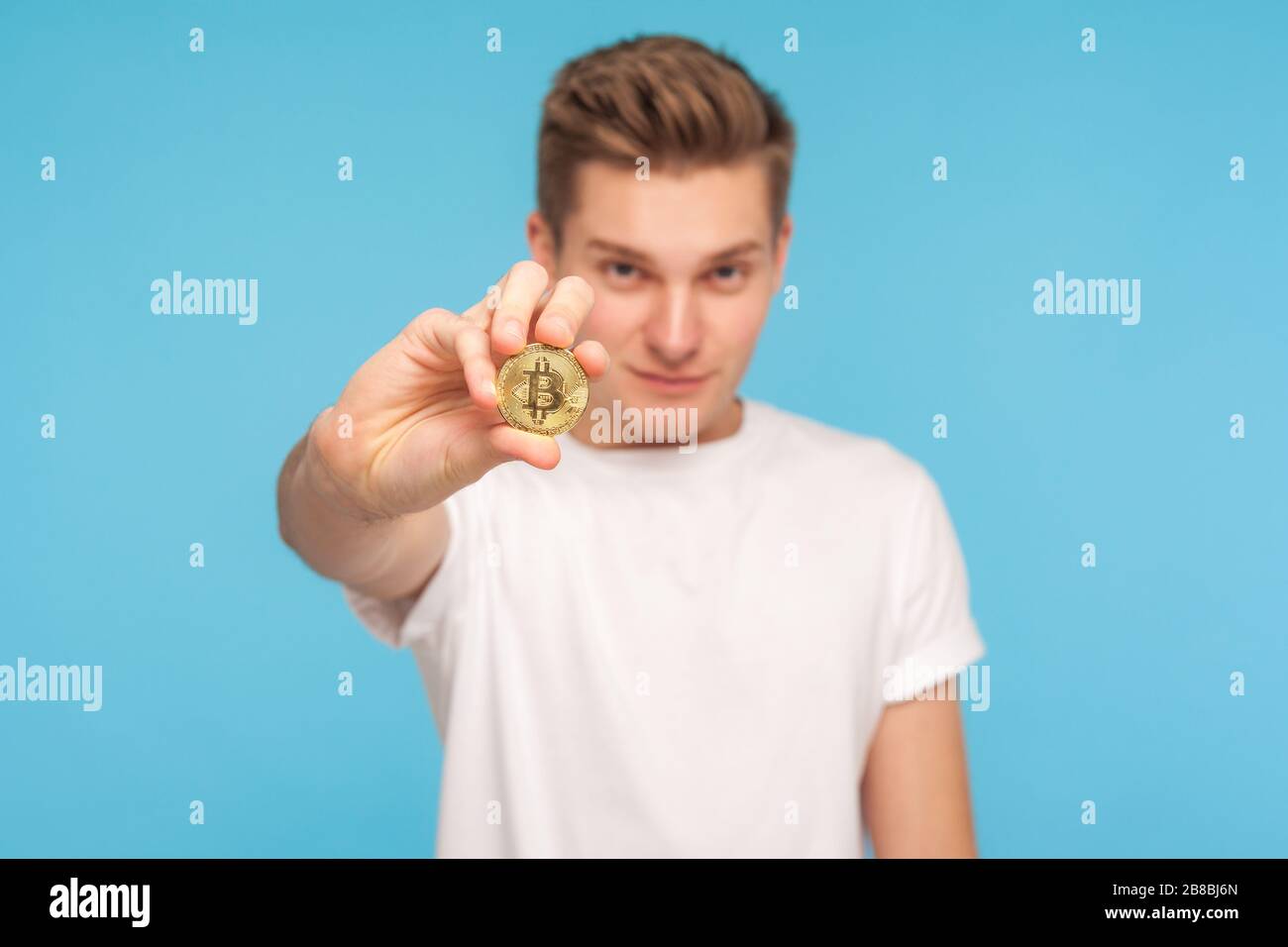 Portrait of young trendy rich man in white t-shirt holding golden ...