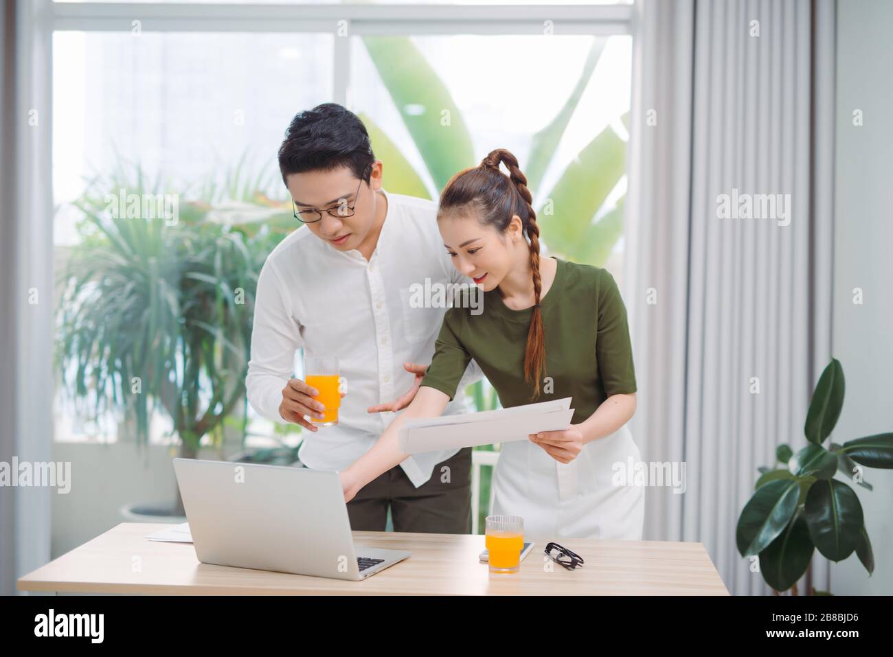Beautiful young couple in office, using laptop Stock Photo - Alamy