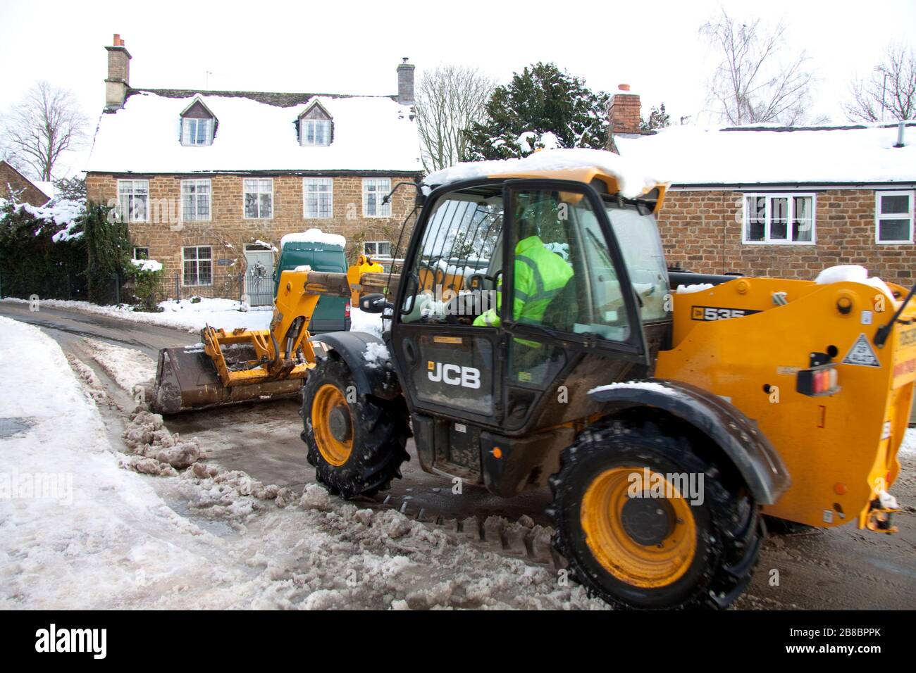 Jcb clearing snowy road Hook Norton Stock Photo - Alamy