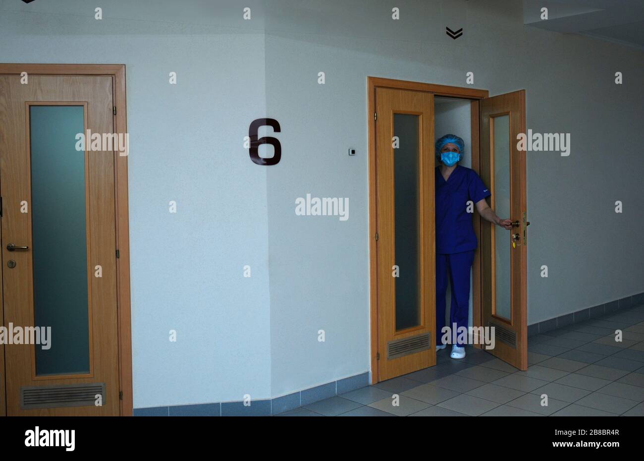 Nurse in face mask and lab coat opening door to the unit of a hospital ...