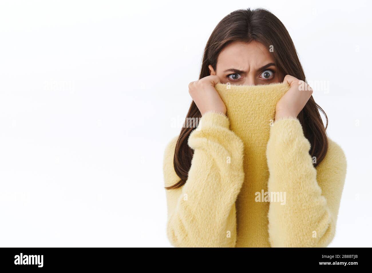 Close-up portrait of funny cute woman hiding face with sweater collar ...