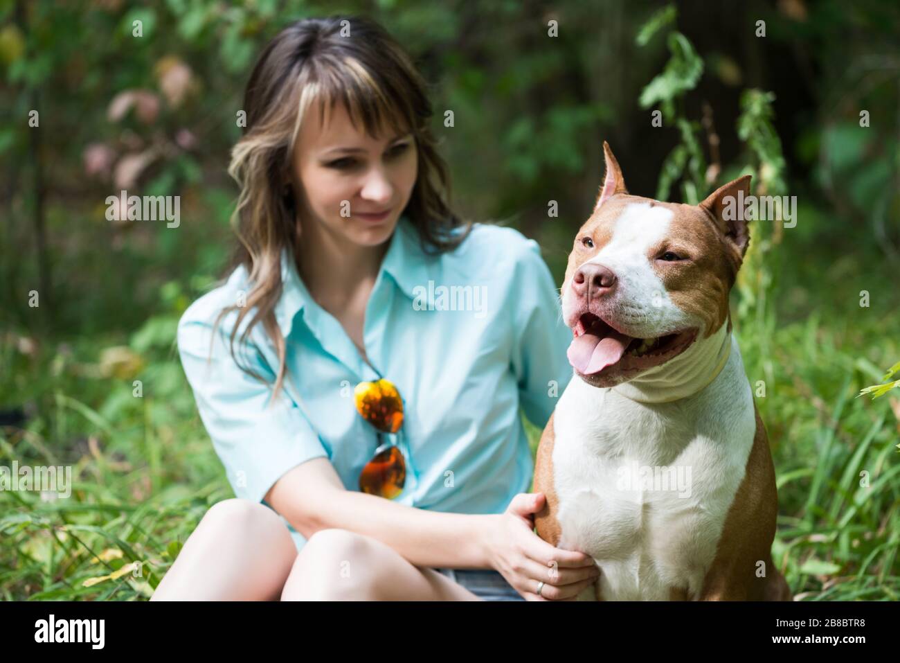 Front view of charming lady resting on grass and holding dog paw. Cute ...