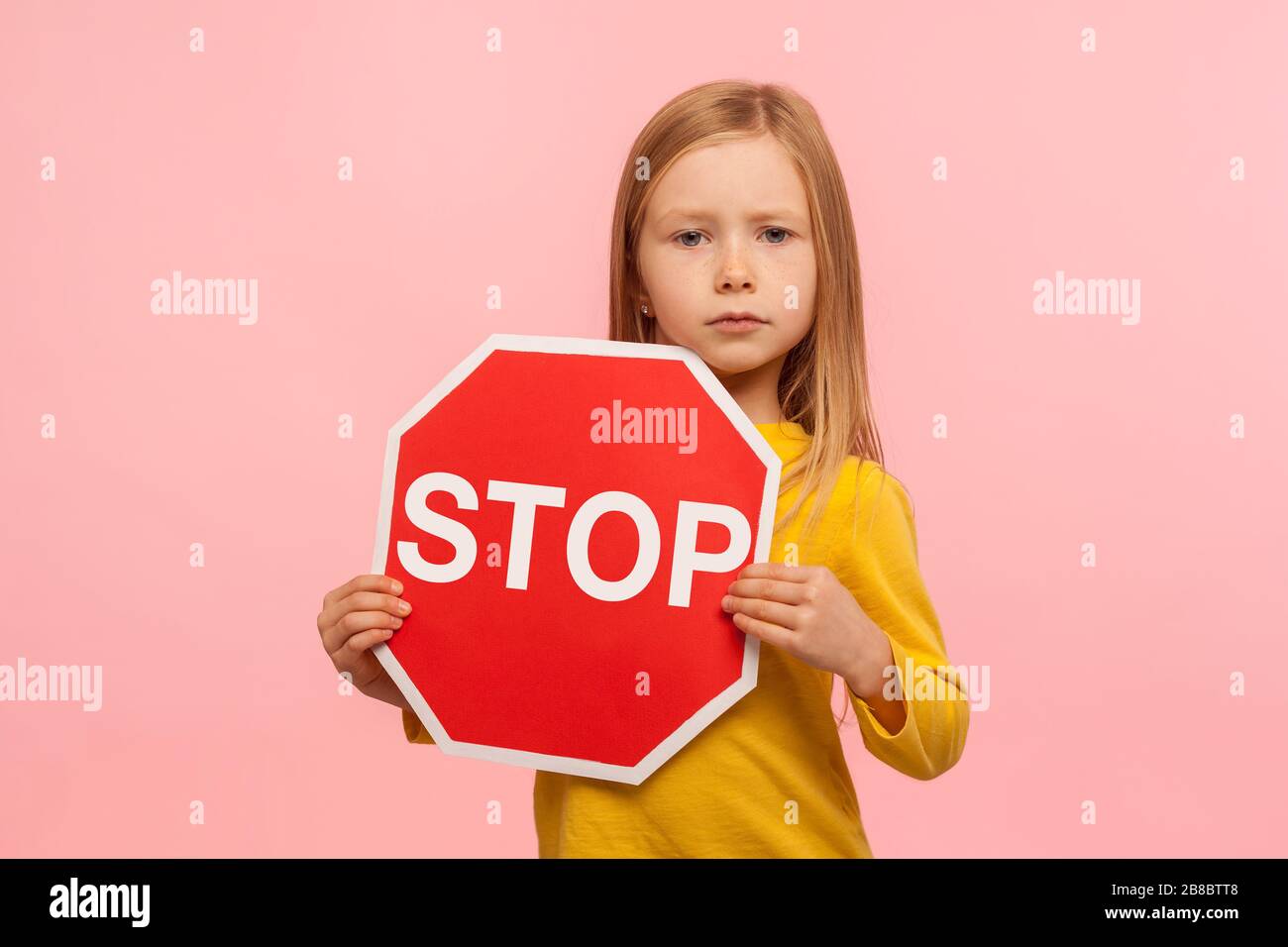Portrait of cute little girl holding Stop symbol, red traffic sign and ...