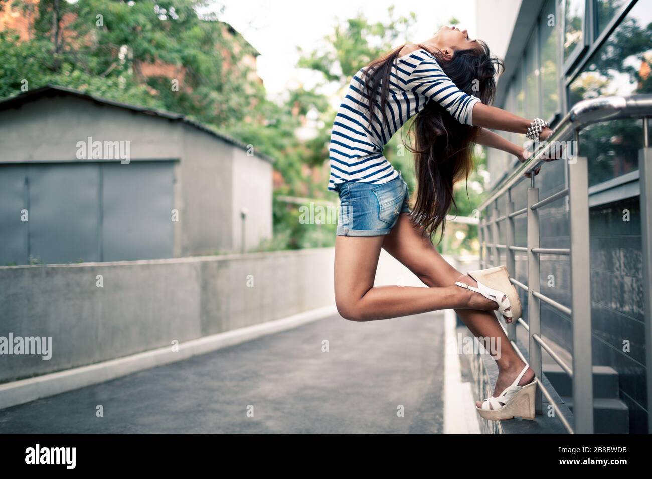 Side view of beautiful young lady gripping handrails and bending ...