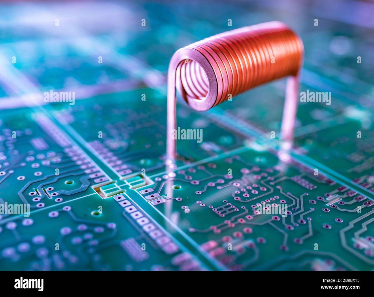 Closeup twisted copper wire stands on a green microcircuit. Computer ...