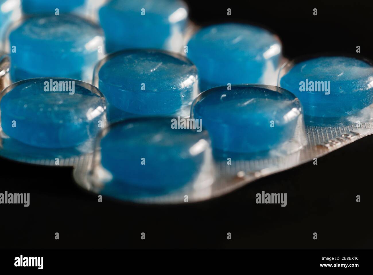 Blue coated tablets in blister packaging on the black background Stock ...