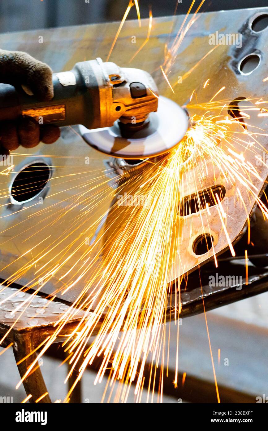 A worker using a grinder cut metal. Processing a metal product using a ...