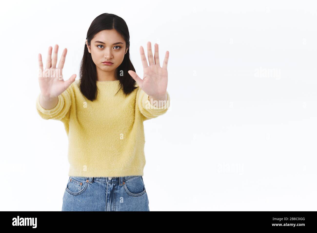Stop right there. Serious-looking asian girl pulling hands forward in ...