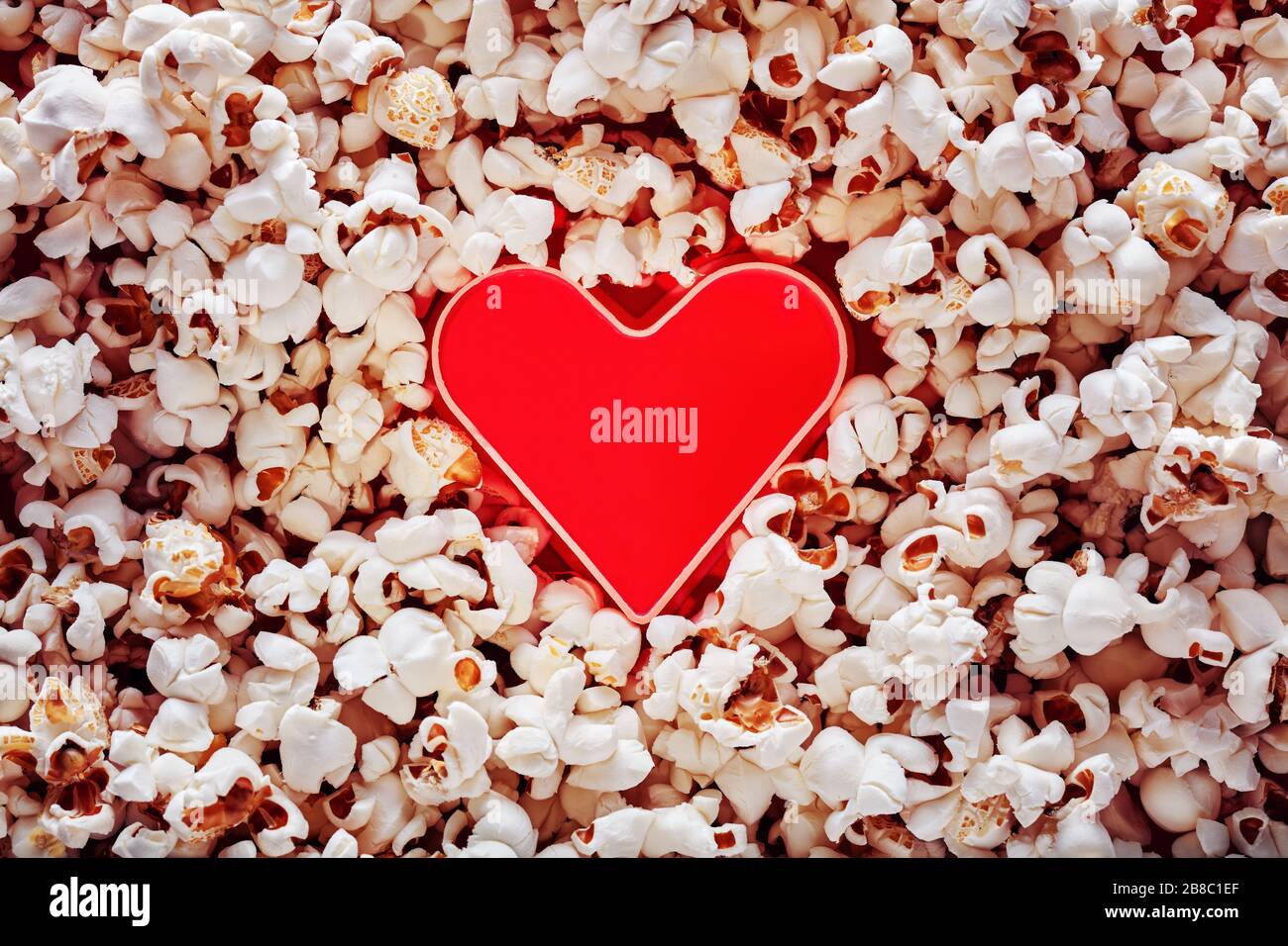 Heart shape in a heap of popcorn with copy space. Watching romantic ...