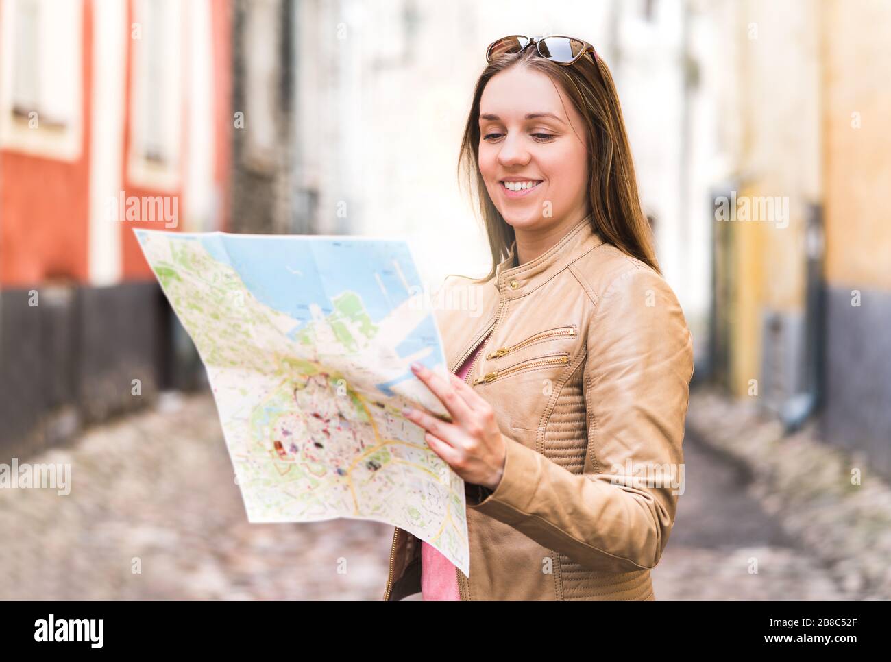 Happy young woman reading map. Smiling traveler navigating and planning ...