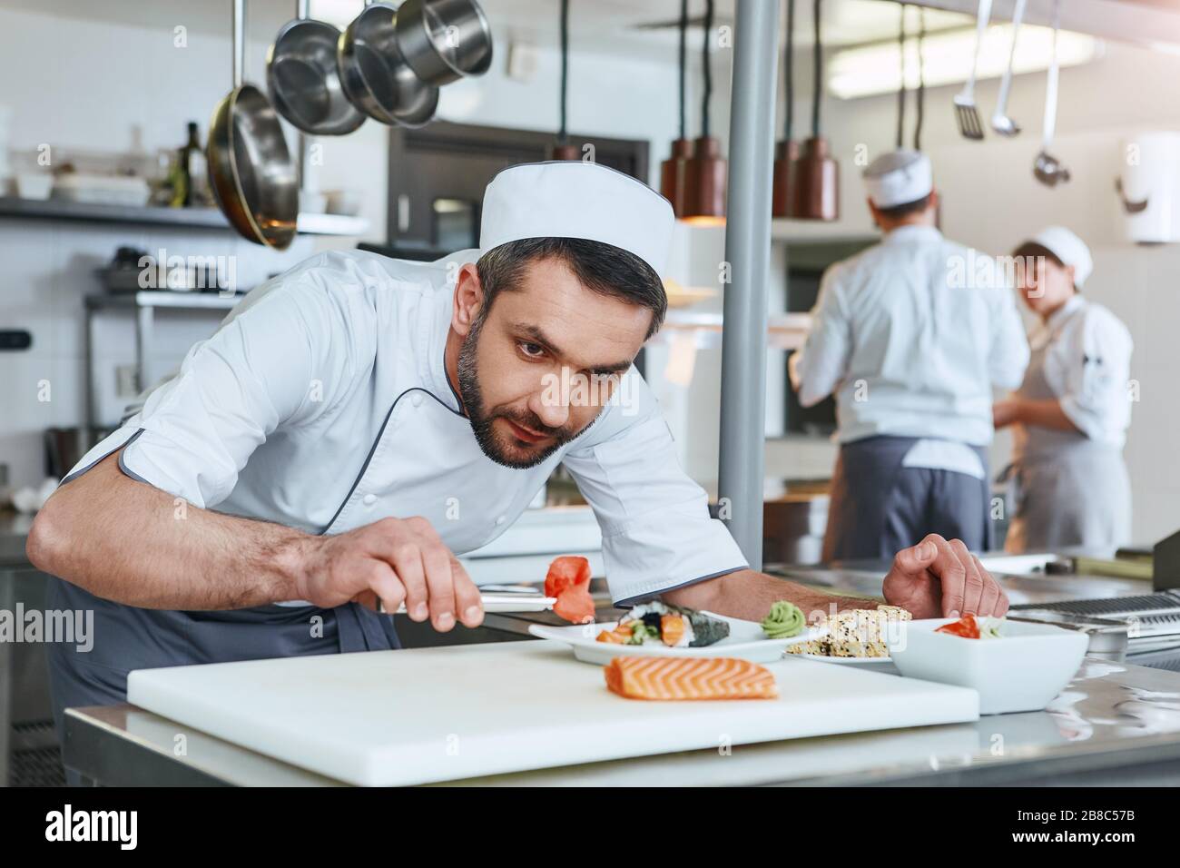 Chef making sushi at restaurant. He concentrates on serving traditional ...