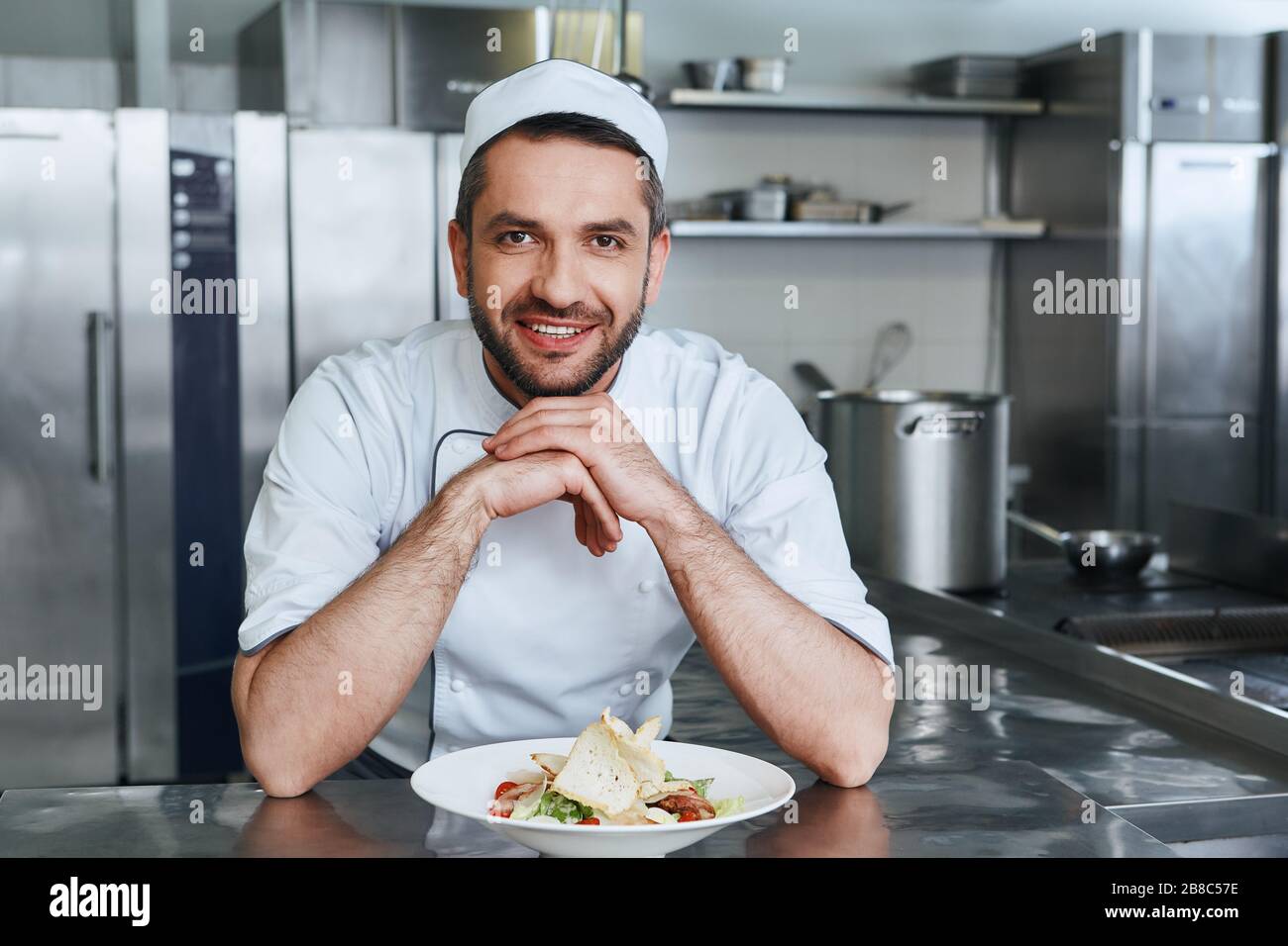 Smiling cook standing over the dish and looking at the camera ...