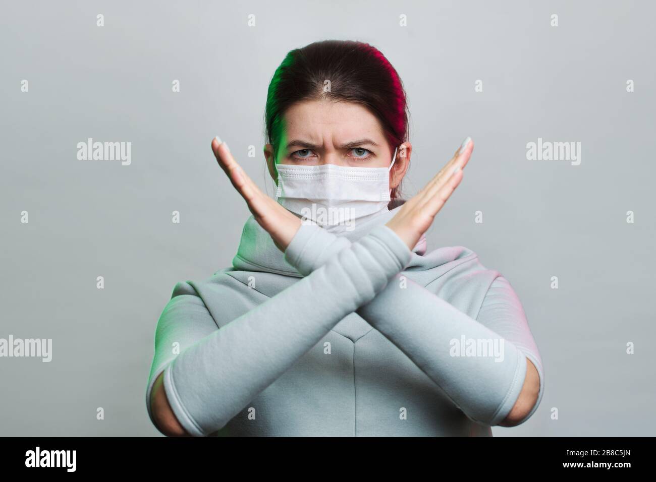 Brunette girl in medical mask with arms crossed isolated in studio on ...