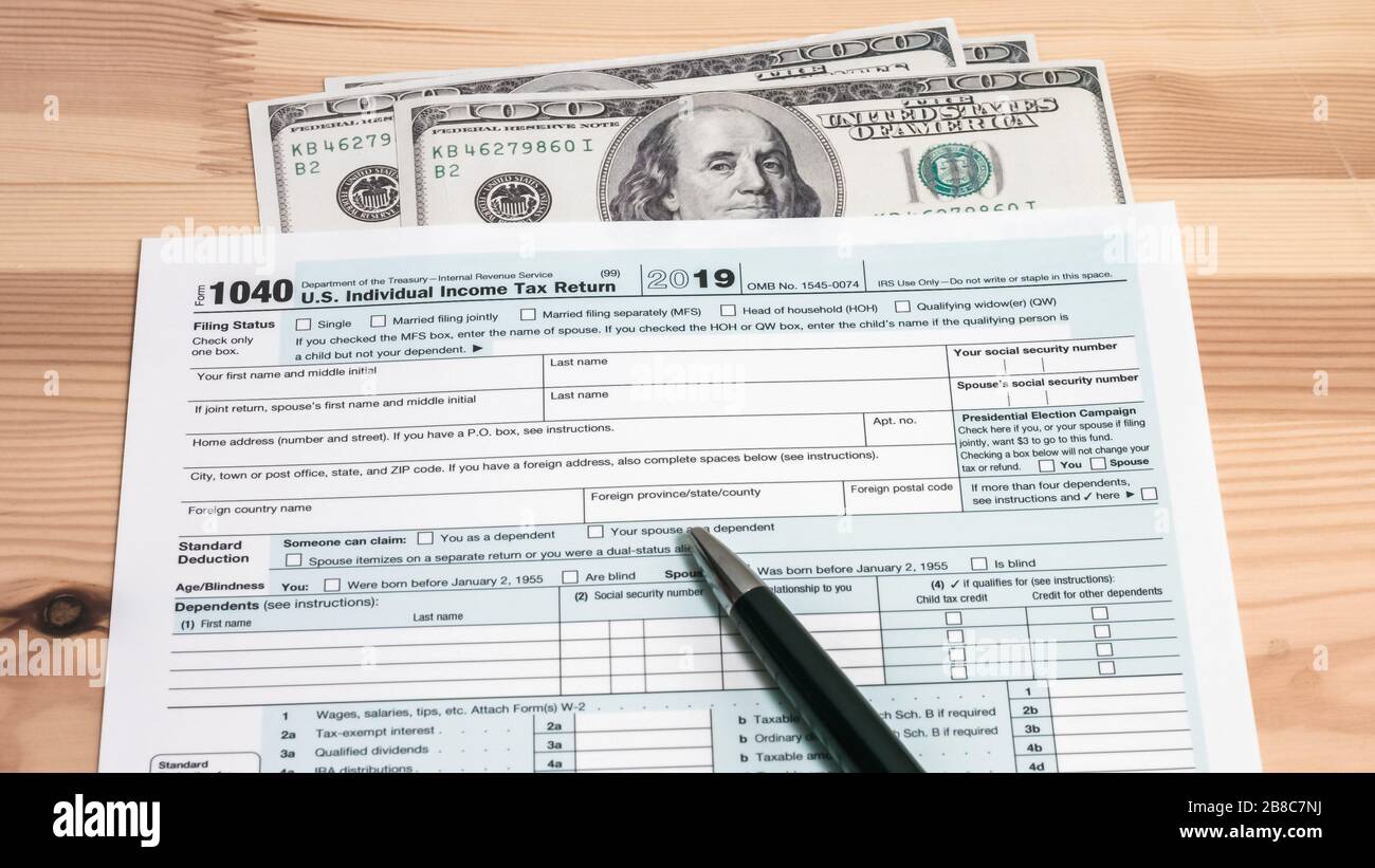 US 1040 tax return form with 100 usd dollar bills and a pen Stock Photo ...