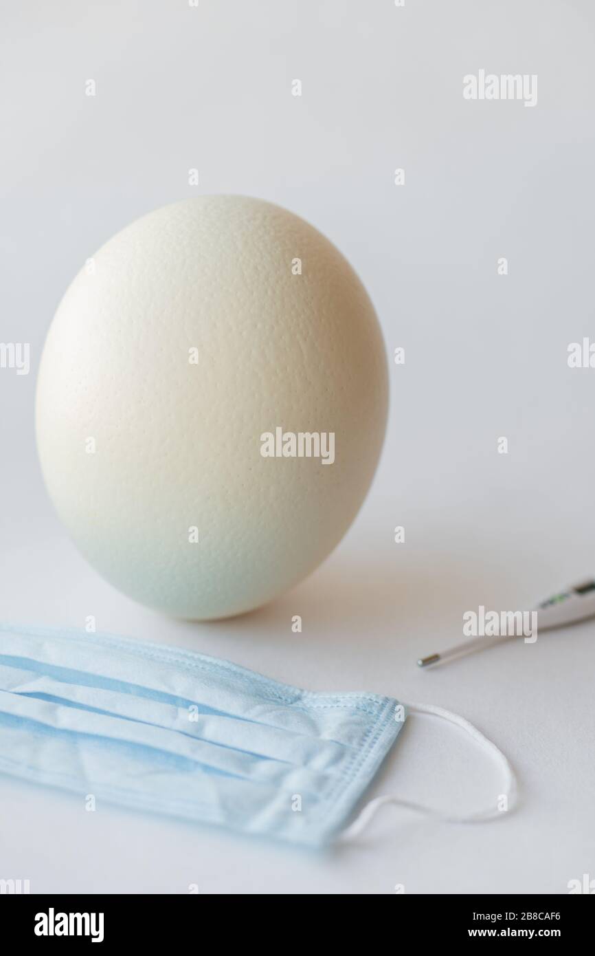 Large white easter ostrich egg, medical mask and thermometer. Egg ...