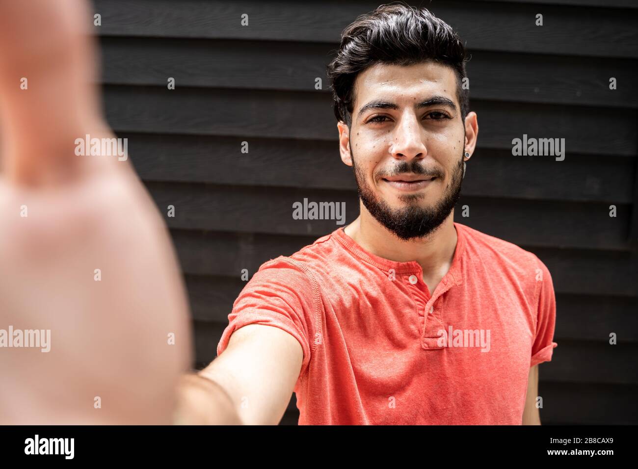 Young Arabian man making a selfie with a camera in the street in front ...