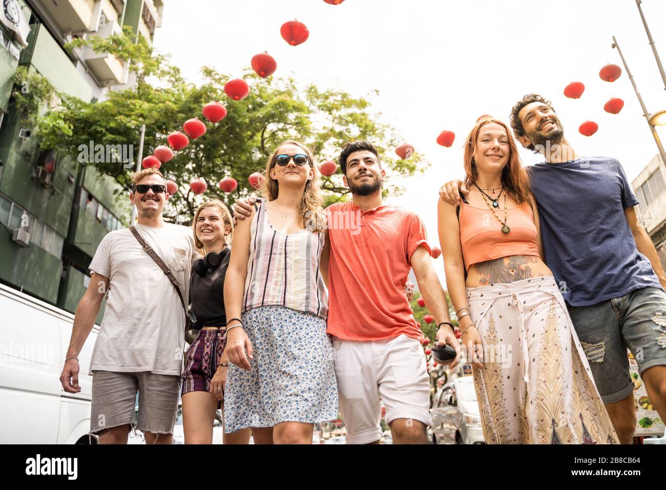 three couples of different ethnicities hugging in a street decorated ...