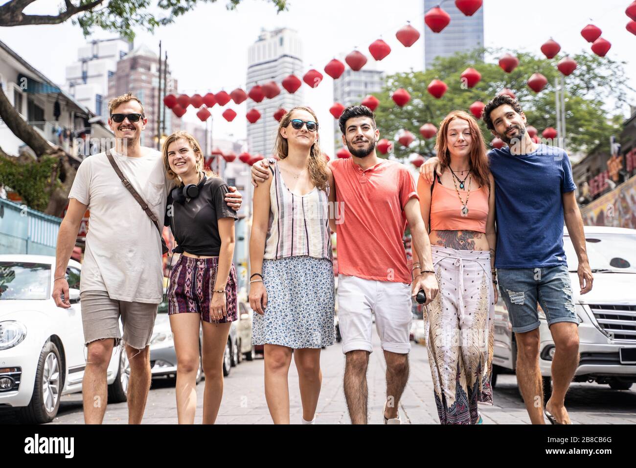 three couples of different ethnicities hugging in a street decorated ...