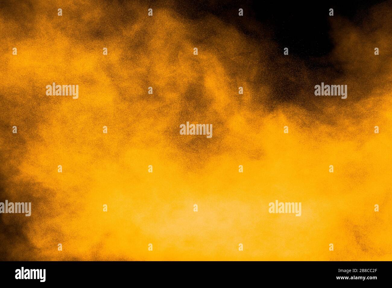 Abstract explosion of orange dust on black background. Freeze motion of ...