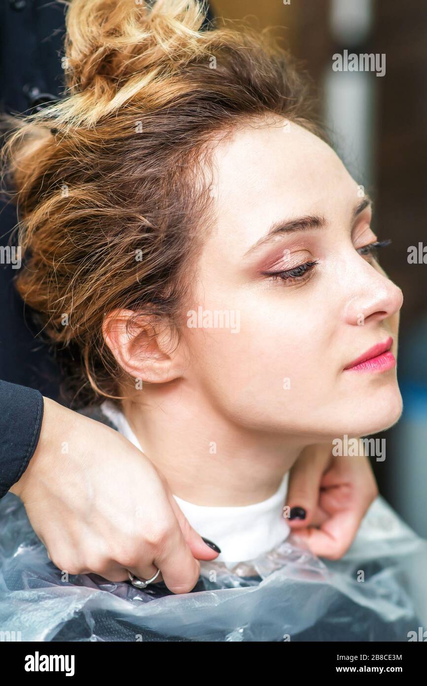 Hairdresser puts plastic sheet to cover his client before hair coloring ...