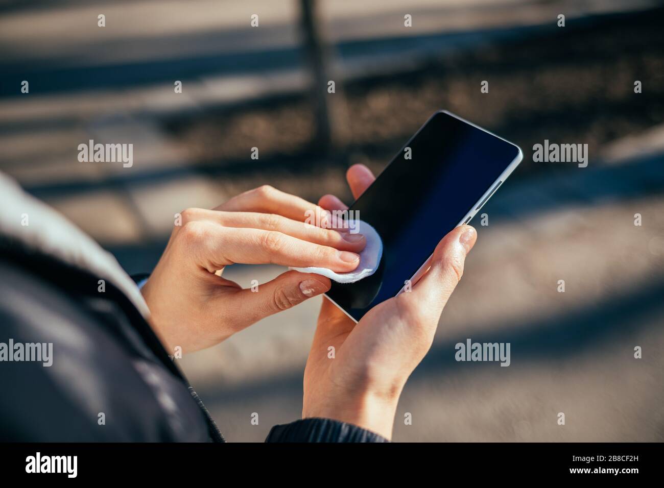 Close-up female hands cleaning mobile phone screen with disinfectant ...