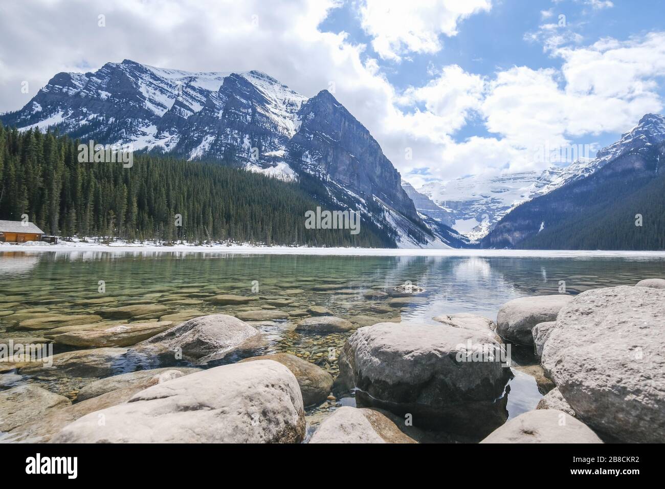 Mount fairview, partly frozen lake, rocks in foreground. Lake Louise ...