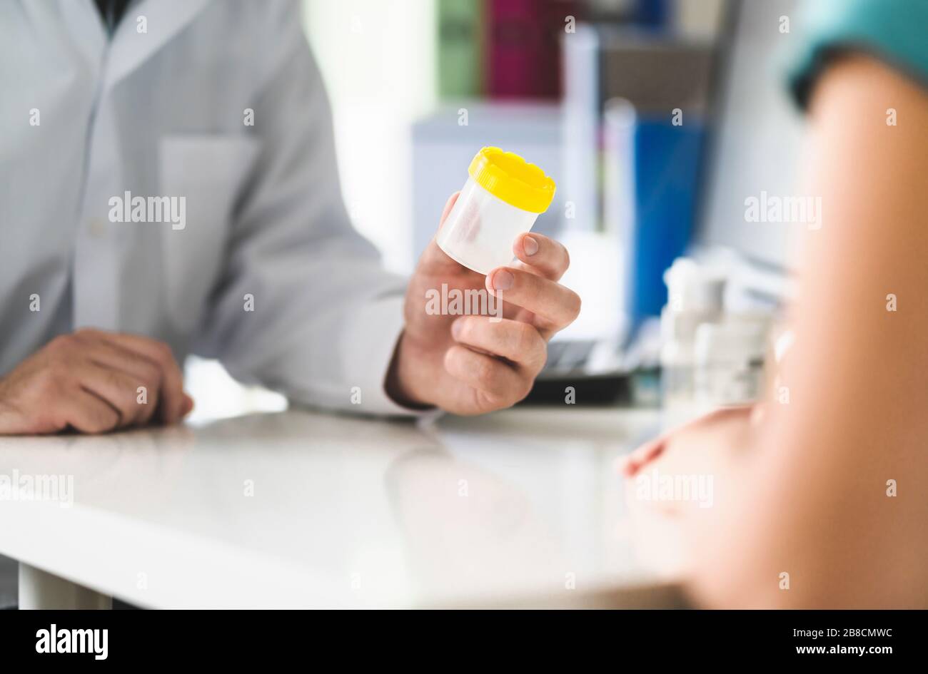 Doctor, patient and urine test cup. Physician giving pee container to a ...