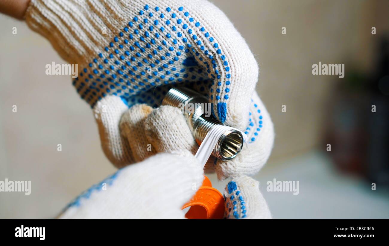 Close up of A man is sealing tape wrap around iron water tap screw ...
