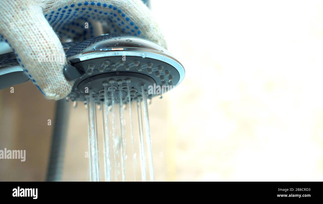 Close - up of gloved hands plumber checks the work of the shower. He ...