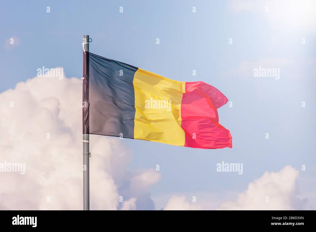 The National flag of Belgium flay over the blue sky. Toned Stock Photo ...