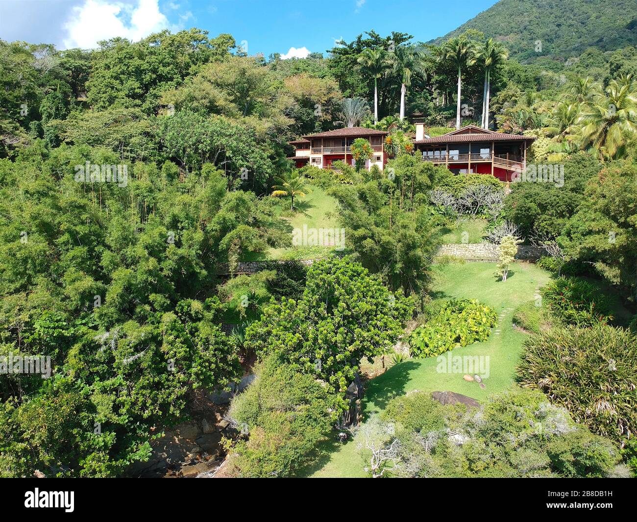 Aerial view of luxury wood house in tropical forest surrounded by trees ...