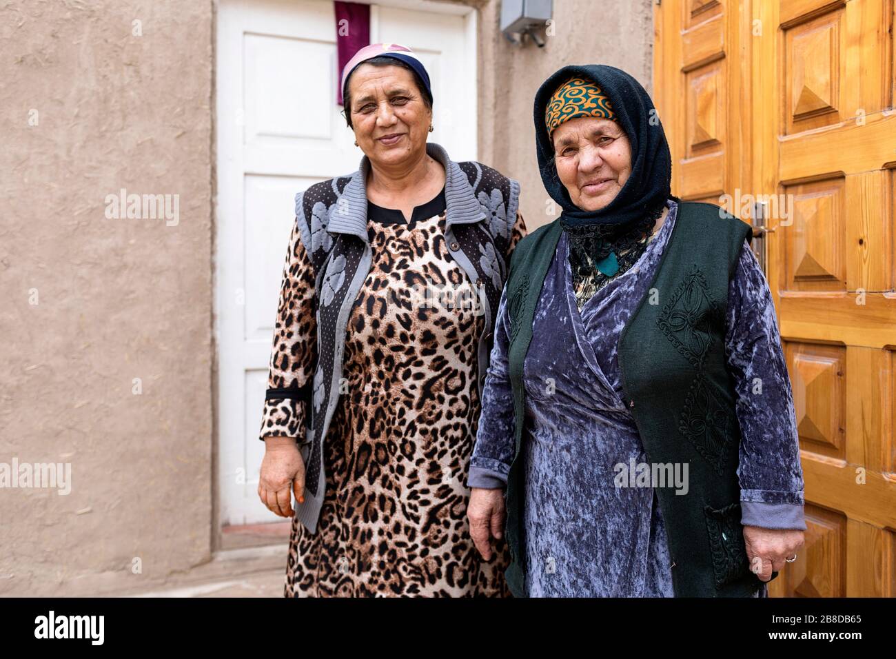 Two old traditionally dressed women in winter in the old town of Khiva ...