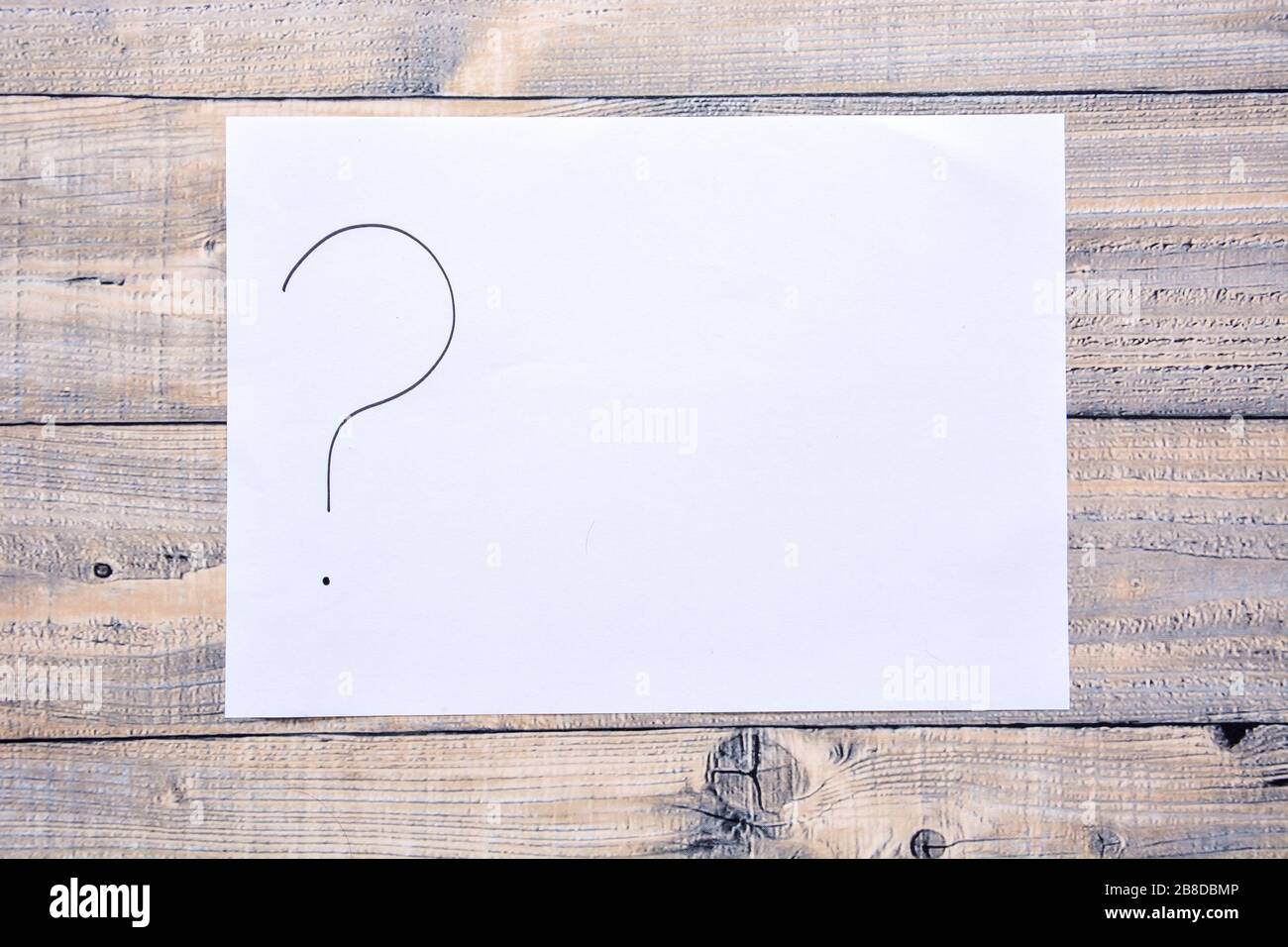 A sheet with a question mark on a wooden background Stock Photo - Alamy