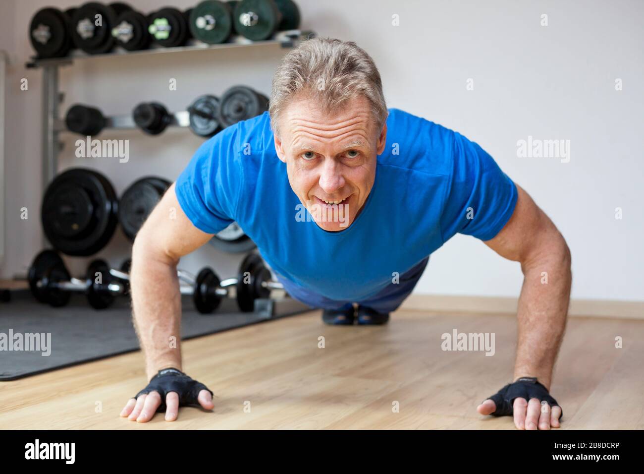 Mature smiling man doing push-ups in a gym - focus on the face Stock ...